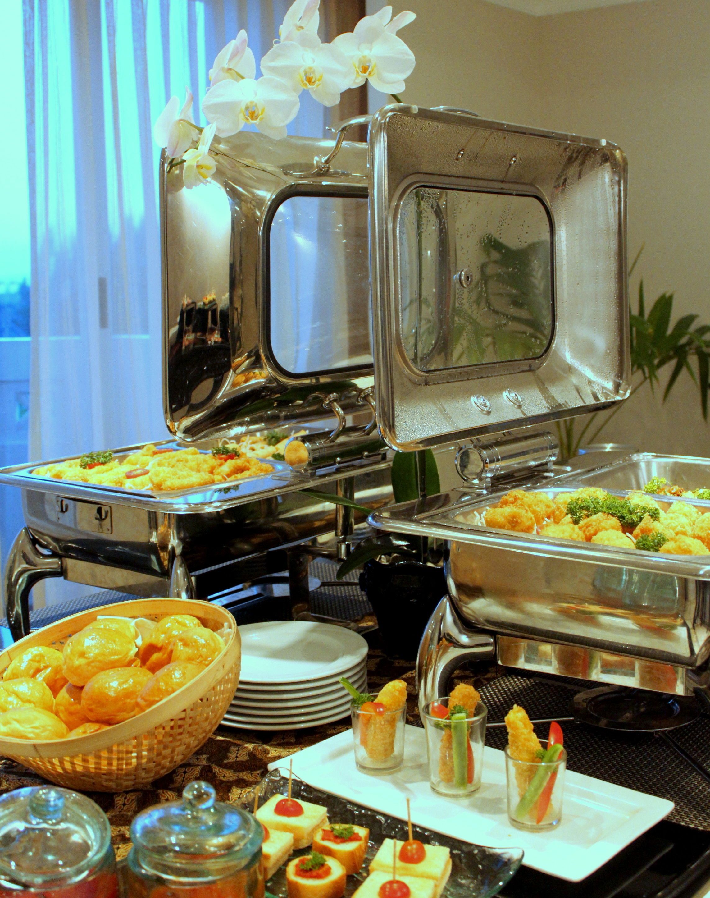 Disposição de buffet com diversos alimentos e um vaso decorativo de flores brancas.