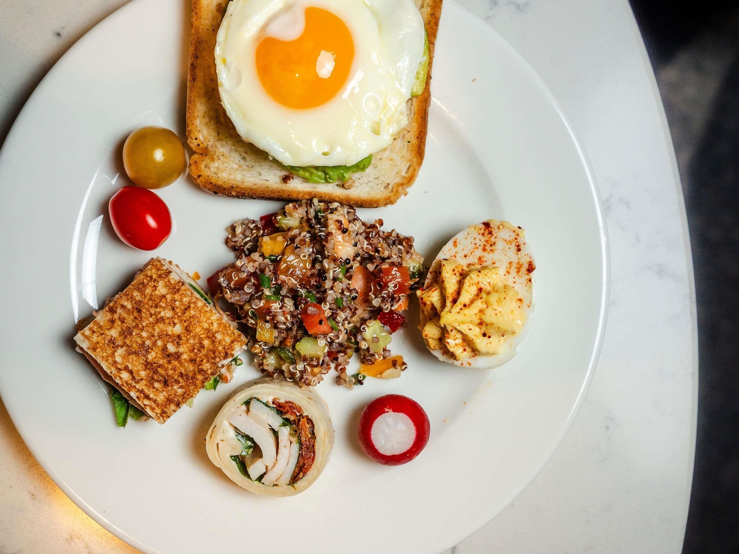 Um prato com ovo frito, salada de quinoa, um wrap de legumes e um rabanete pequeno.