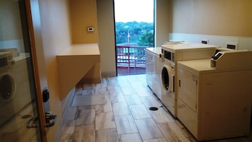 Uma lavanderia com máquina de lavar, secadora e uma pequena janela.