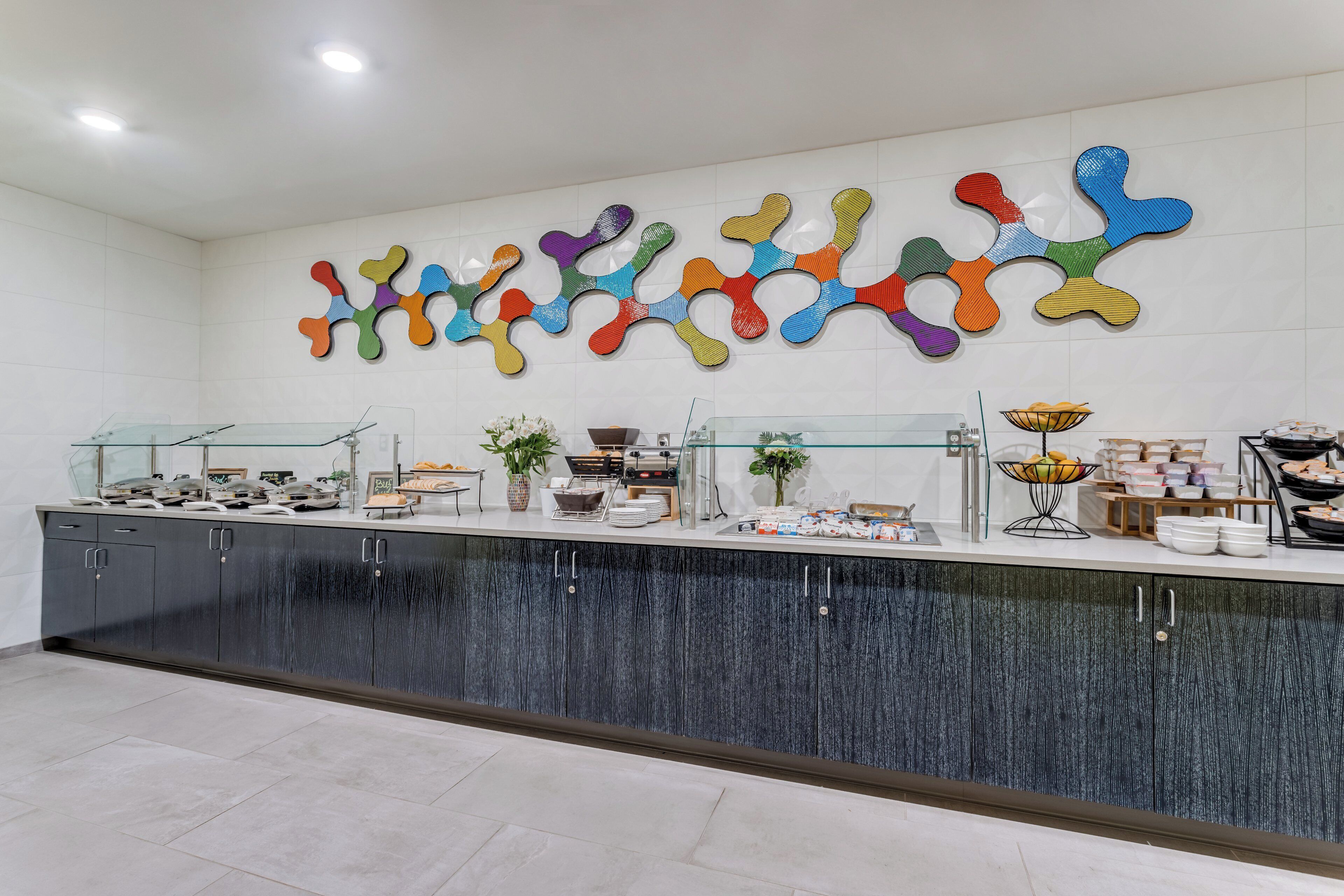 Uma área de buffet com diversos tipos de comida e um painel decorativo.