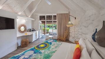 Quarto com cama, televisão, escrivaninha, cadeira e vista para o exterior.