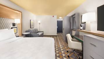 Quarto de hotel com cama, escrivaninha, cadeira, abajur e máquina de café.