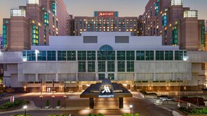Um hotel Marriott com entrada imponente, grandes janelas e fachada bem iluminada.
