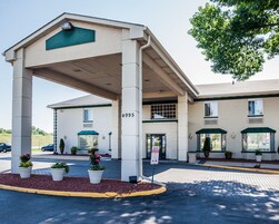 Entrada de hotel com área de espera coberta, número 4995, e plantas em vasos em primeiro plano.
