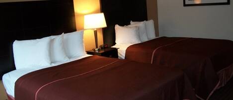Quarto de hotel com duas camas, uma mesa de cabeceira, um abajur e um quadro na parede.