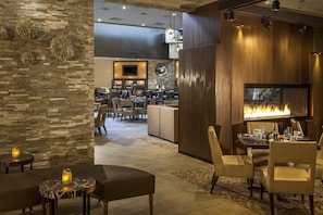 Um restaurante moderno com parede de pedra, lareira e área de bar.