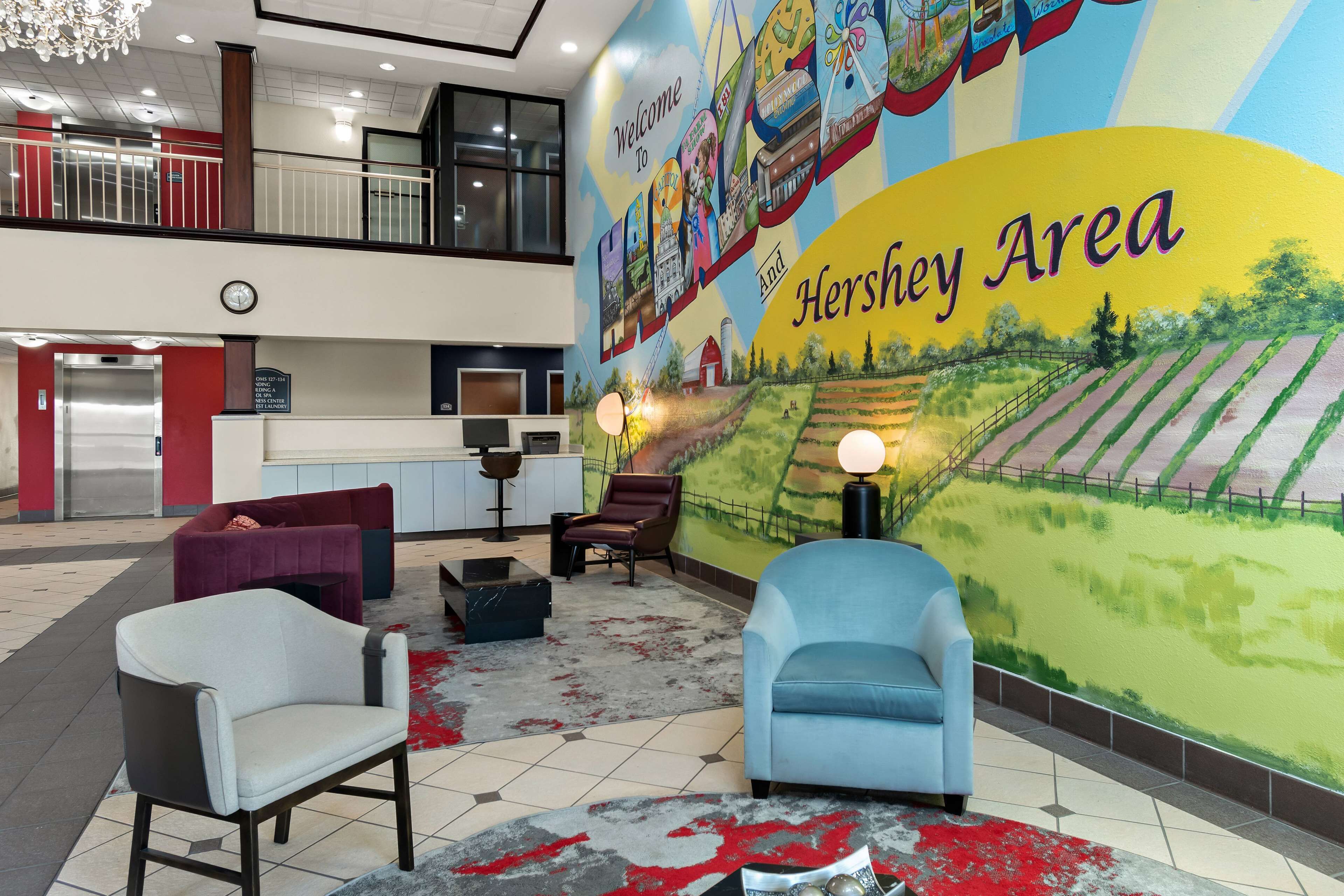 Um hall com um mural da região de Hershey, uma receção, um relógio e áreas de estar.