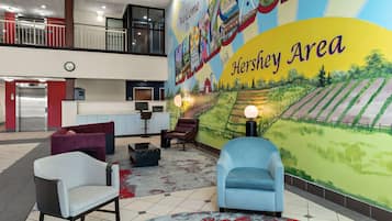 Um hall com um mural da região de Hershey, uma receção, um relógio e áreas de estar.