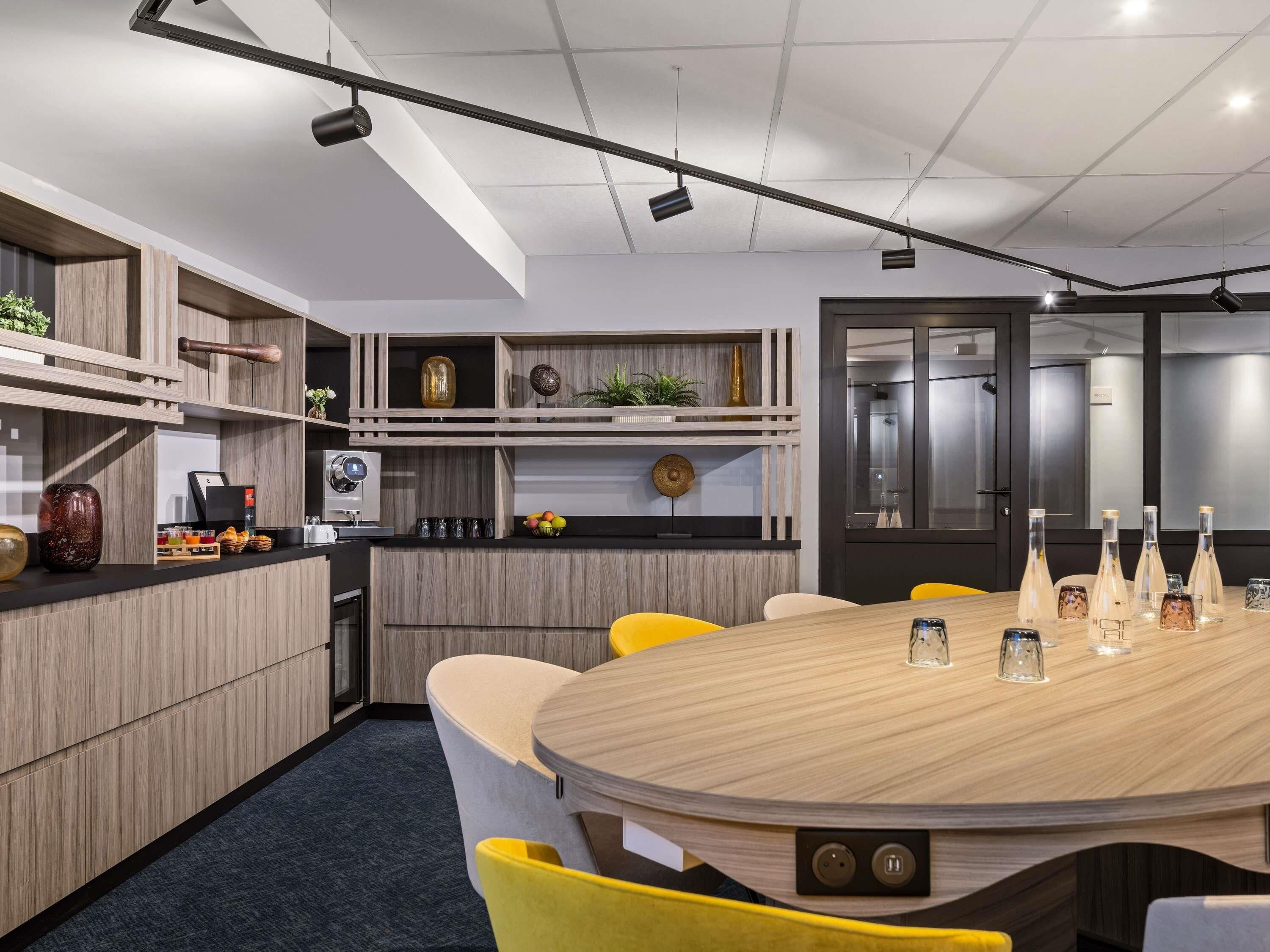 Uma cozinha moderna com mesa redonda de madeira, cadeiras amarelas e máquina de café integrada.