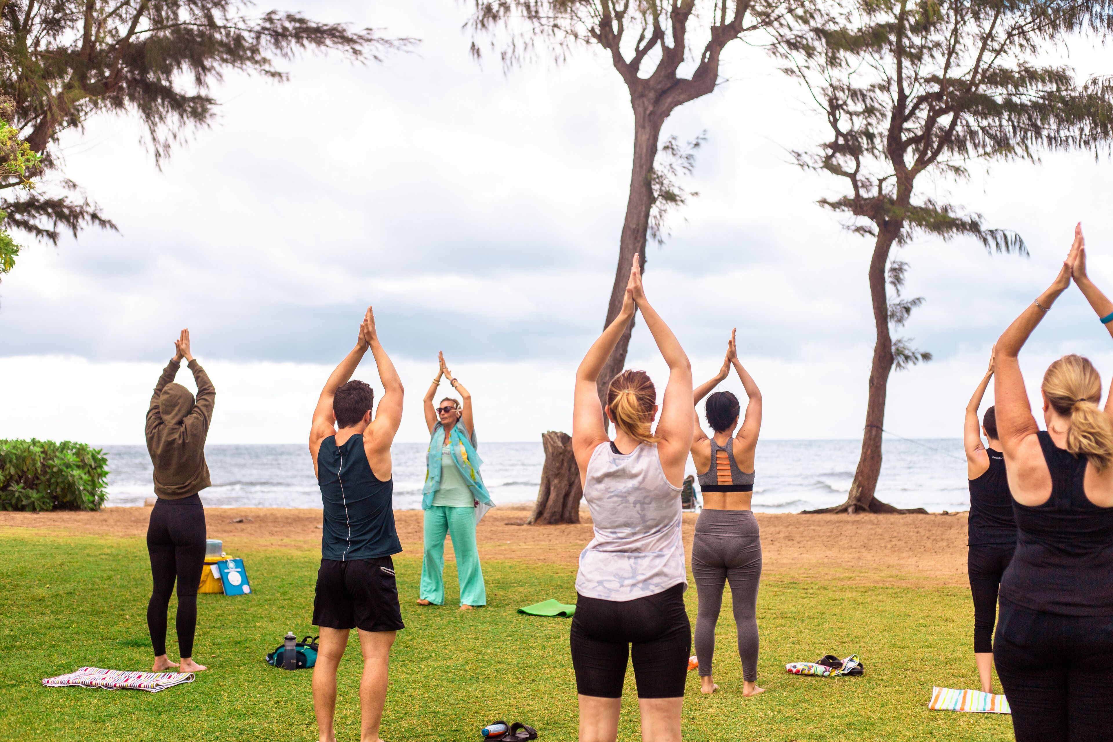 Um grupo de pessoas praticando yoga ao ar livre, com vista para o oceano.
