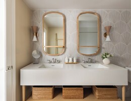 Casa de banho com duas pias, um espelho e um vaso com flores.