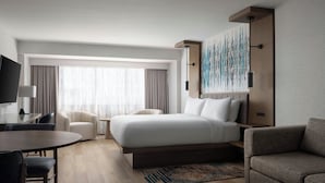 Quarto de hotel moderno com uma cama grande, uma escrivaninha, um sofá e uma televisão.