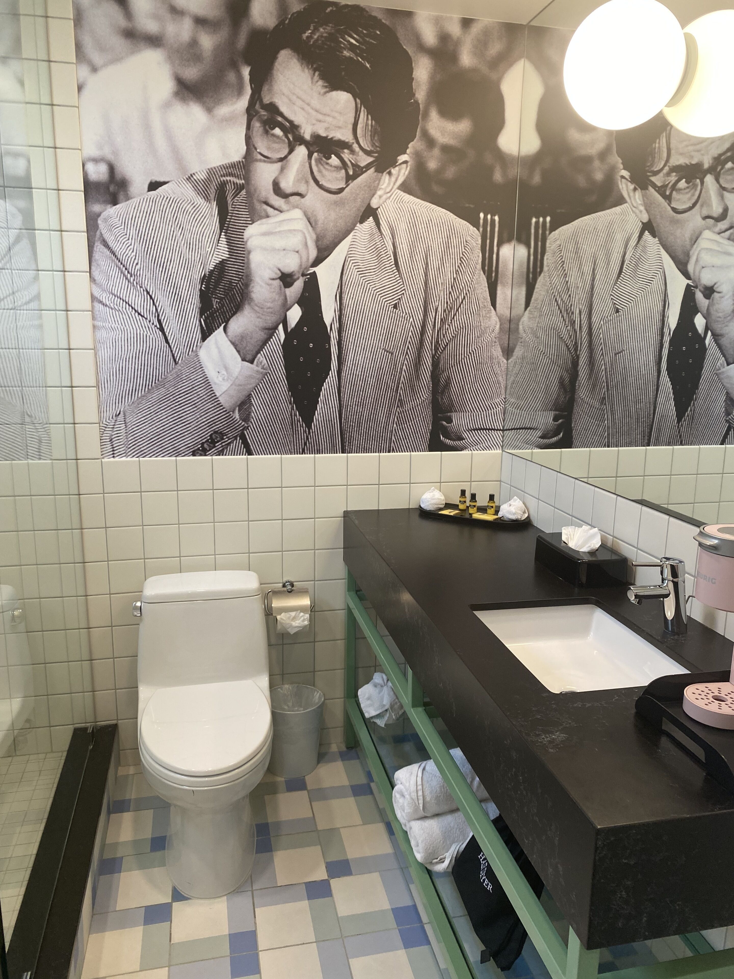 Um banheiro com vaso sanitário, pia, espelho e piso revestido de azulejos.