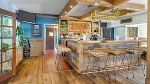 Uma área de bar com vigas de madeira, banquetas e balcão.