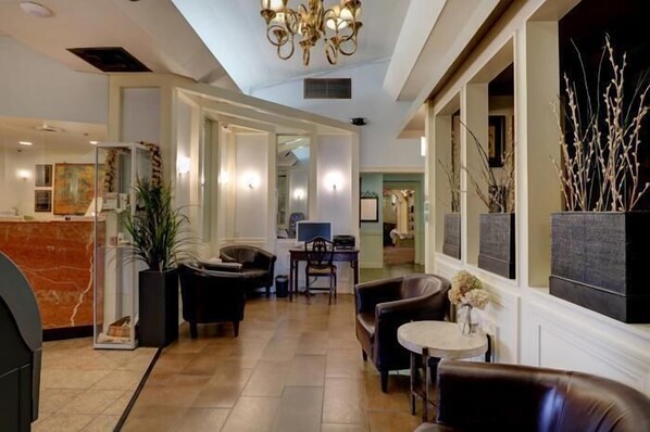 Um hall amplo com balcão de recepção, assentos de couro e um lustre.