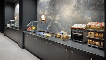 Buffet com diversos alimentos e um mural decorativo ao fundo.