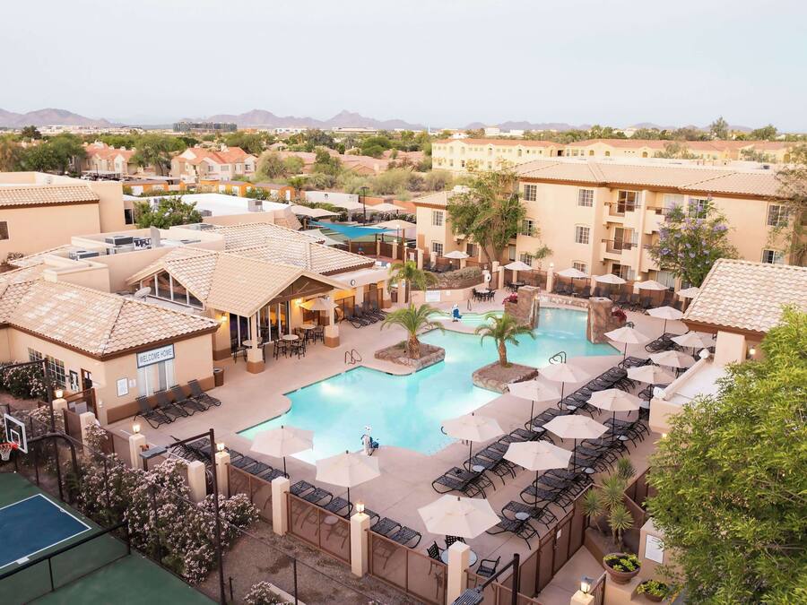 Resort com piscina, área de estar externa e quadra de basquete.