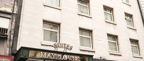 Um edifício com uma placa que diz "Suites Mayflower" e um restaurante chamado "Mayflower" abaixo.