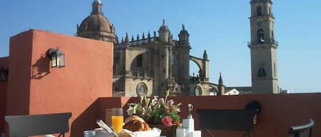 Mesa posta para café da manhã com vista para uma igreja histórica e seu campanário.