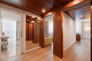Um interior moderno com teto de madeira, banheiro com toucador de mármore e sala de estar com sofá.