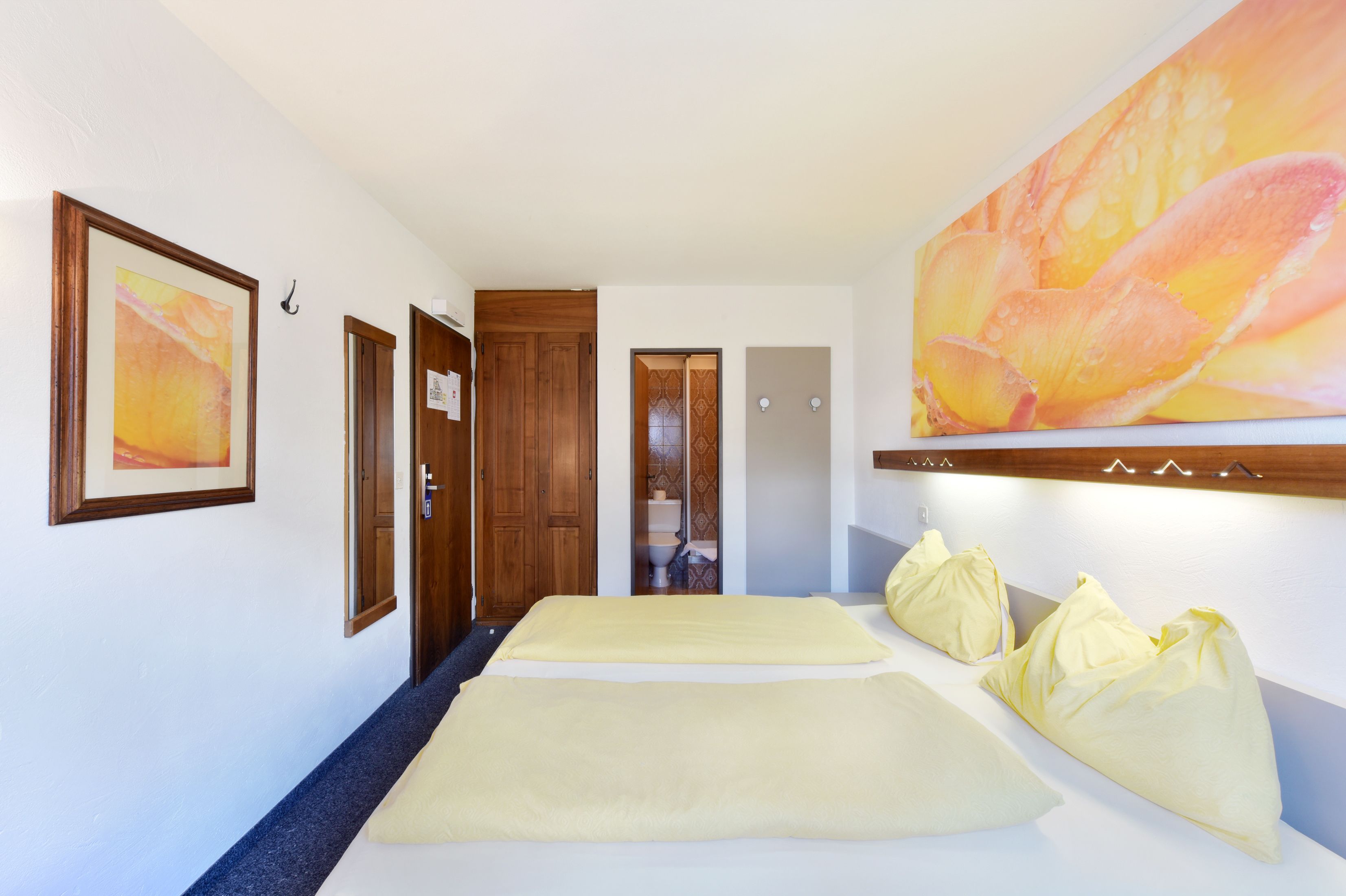 Quarto de hotel com uma cama, um quadro grande e uma porta de madeira.