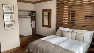 Quarto com cama, persianas de madeira, espelho e quadros nas paredes.