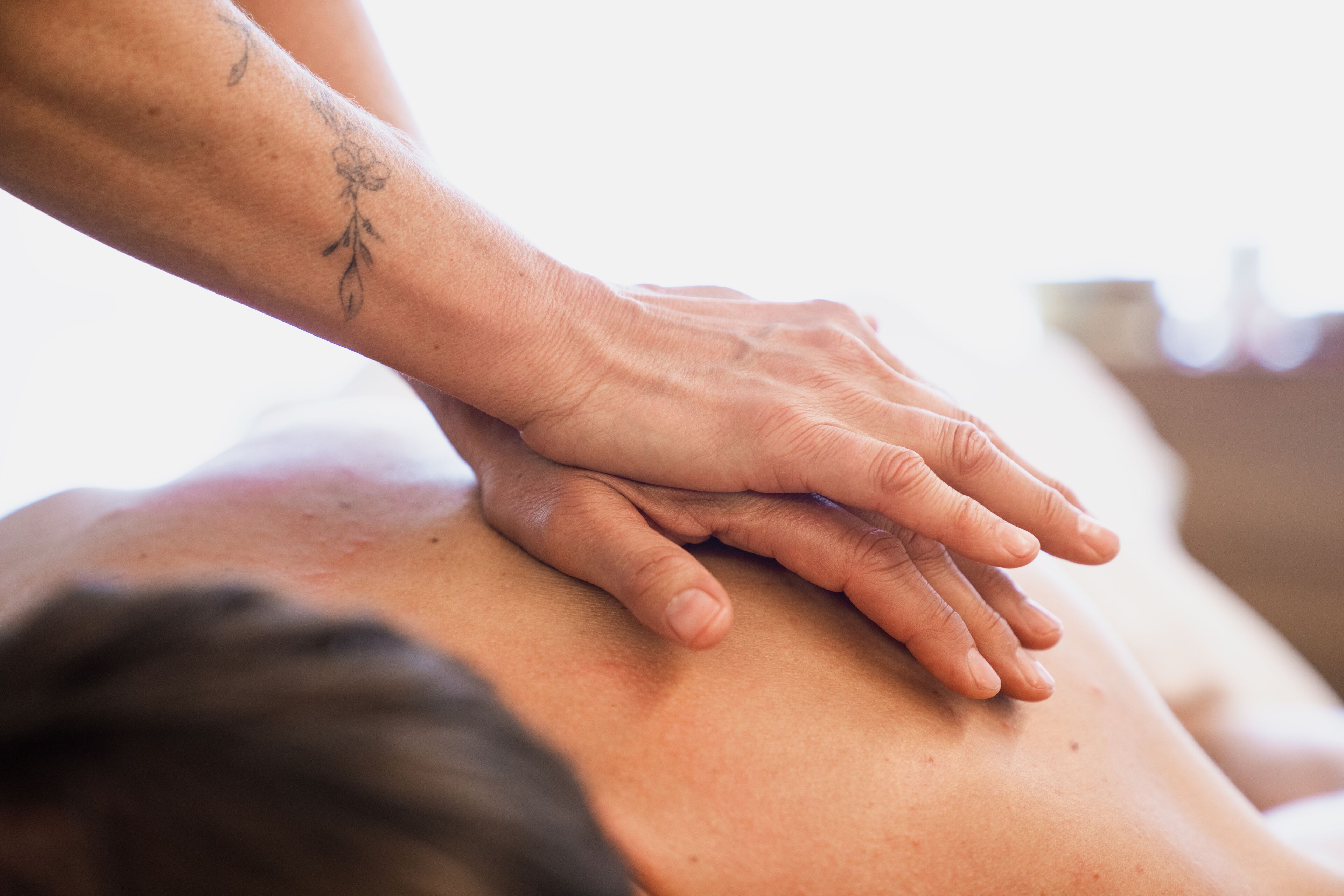 Close-up de mãos massageando as costas de alguém.