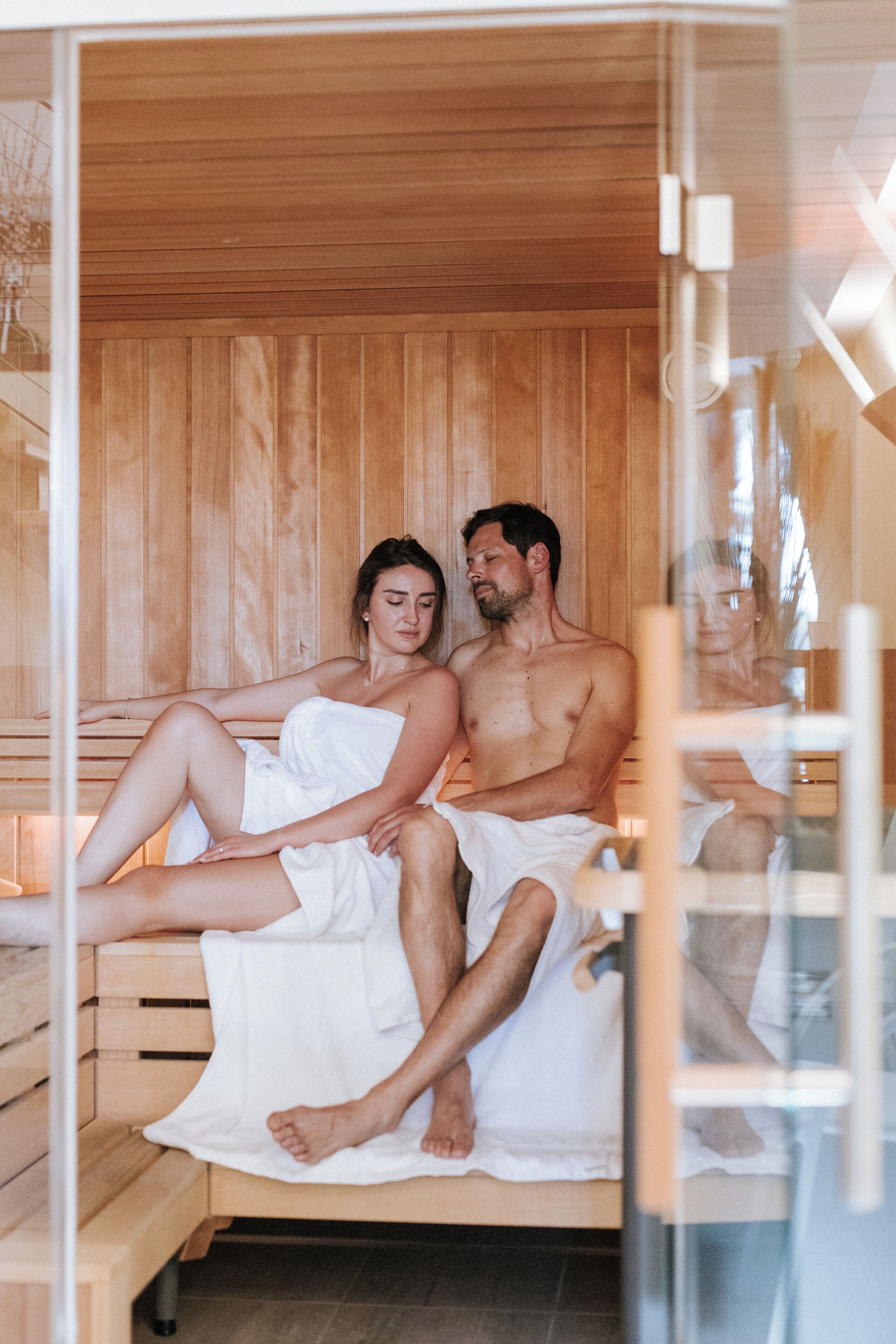 Uma sauna com bancos de madeira e divisória de vidro.