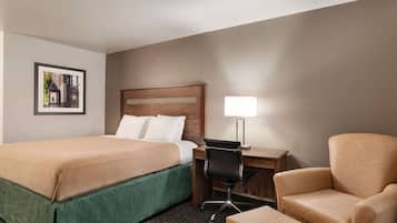 Quarto de hotel com cama, escrivaninha, cadeira e abajur.