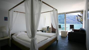 Quarto com cama de dossel, uma escrivaninha e vista para uma paisagem montanhosa.