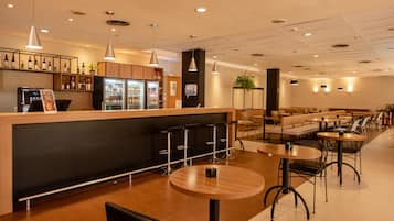 Um café moderno com área de bar, assentos e um refrigerador cheio de bebidas.