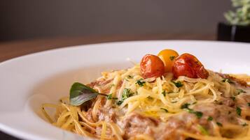 Um prato de espaguete com almôndegas, guarnecido com tomates e ervas.