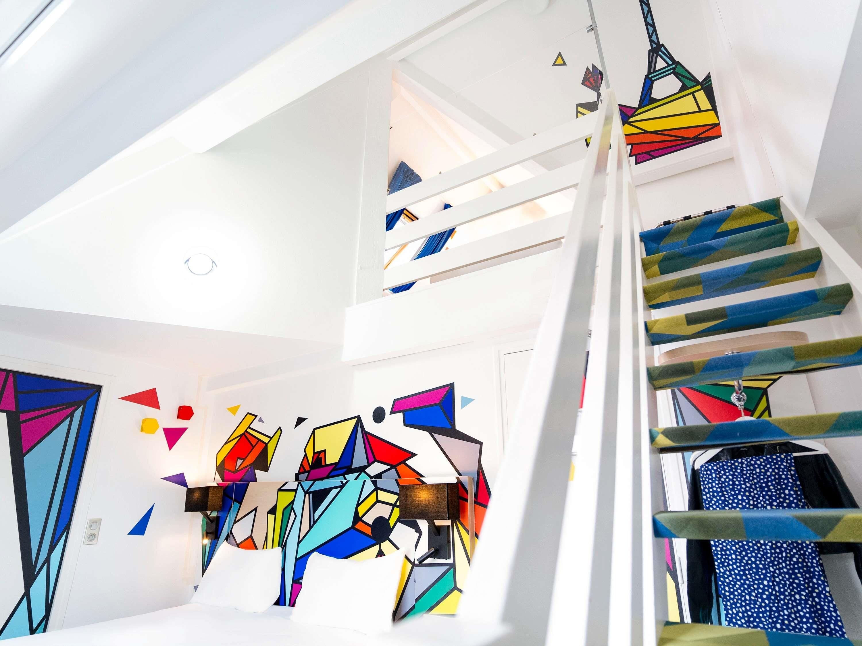 Um interior moderno com escada, arte geométrica na parede e tecido estampado sobre o corrimão.