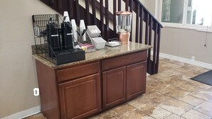 Uma bancada de cozinha com uma máquina de café, um liquidificador e um dispensador de café.