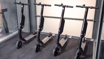 Quatro scooters elétricas estacionadas em fila sobre um tapete.