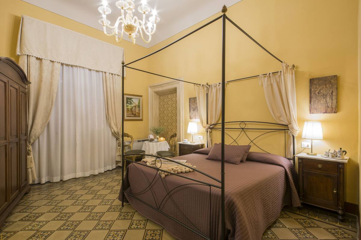 Uma cama com dossel, cabeceira, mesa de cabeceira e um candelabro.