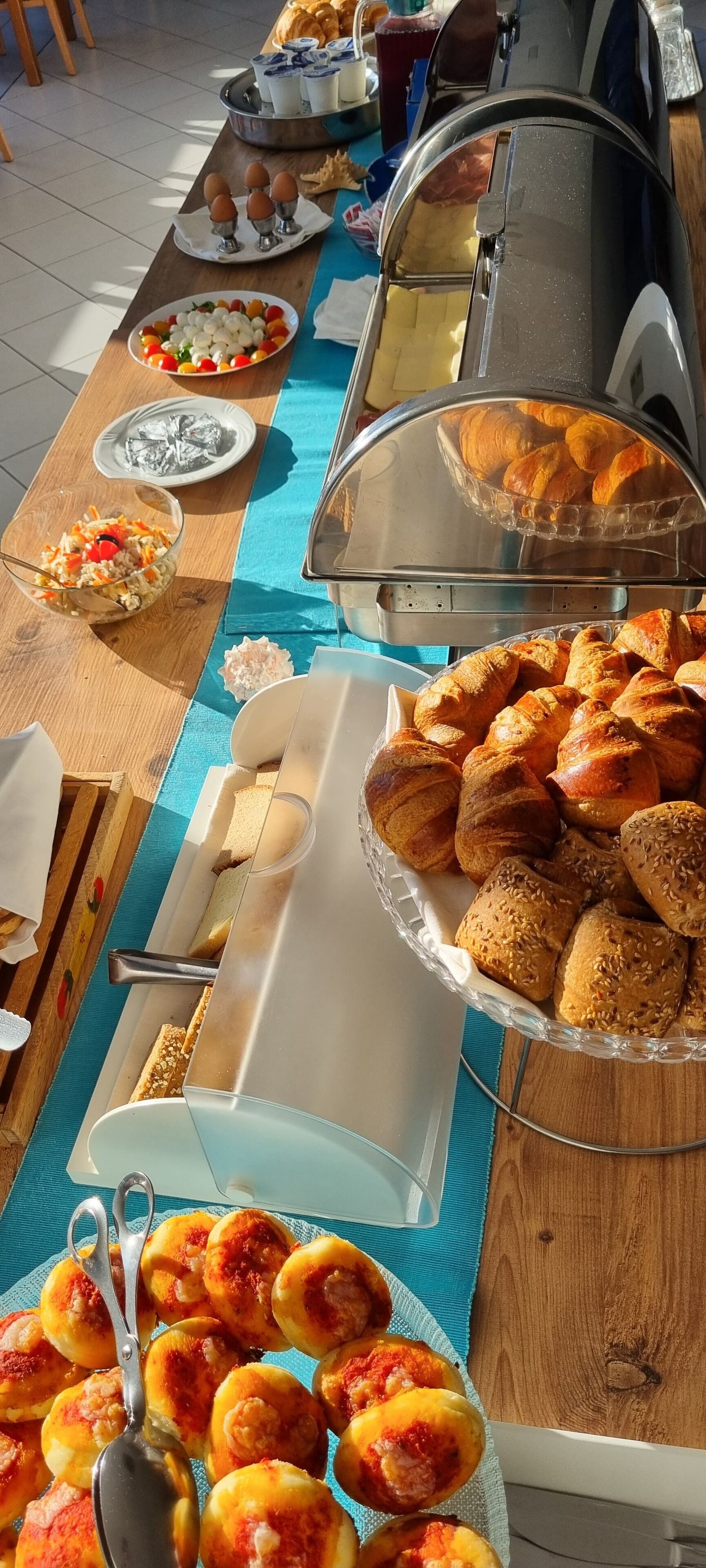 Mesa de buffet com diversos alimentos, incluindo doces, ovos e saladas.