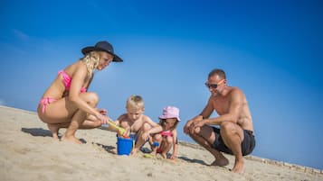 Na praia, espreguiçadeiras, guarda-sóis de praia, voleibol de praia