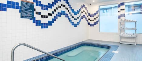 Uma área de hidromassagem com parede revestida e piscina.