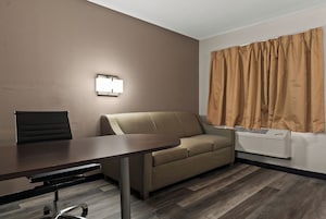 Uma sala de conferências com mesa, cadeiras, um sofá, luminária fixada na parede e um aparelho de ar condicionado.