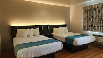 Quarto de hotel com duas camas, cada uma com cabeceira, roupa de cama branca e detalhes em verde-água.