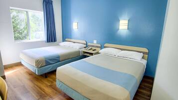 Quarto de hotel com duas camas, uma janela com cortinas e luminárias fixadas na parede.