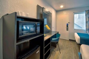 Quarto compacto com cozinha compacta, uma cama, uma escrivaninha e uma cadeira.