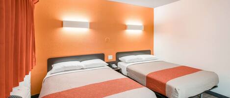 Quarto de hotel com duas camas, paredes alaranjadas e um ventilador de teto.
