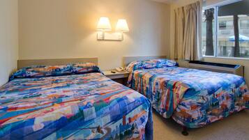 Quarto de hotel com duas camas, uma janela com cortinas, um abajur fixado na parede e um aquecedor.