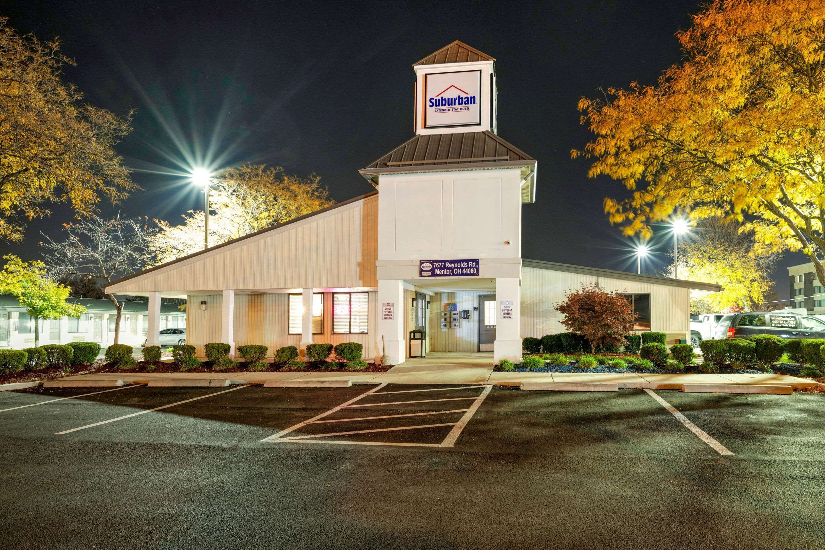 Um Suburban Inn com uma placa visível, estacionamento e entrada bem iluminada.