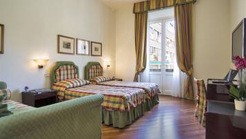Quarto de hotel com duas camas, uma escrivaninha, uma cadeira e uma televisão.