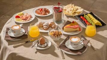 Uma mesa posta para o café da manhã, com pratos de comida, bebidas e doces.