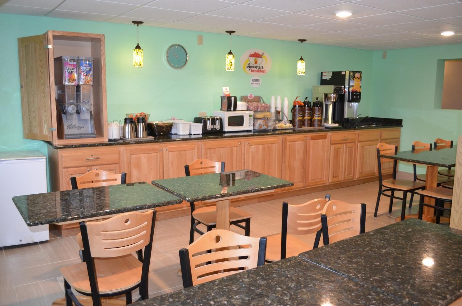 Uma área de café da manhã com armários de madeira, micro-ondas e um espaço para café.