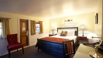Quarto de hotel com uma cama, uma mesa, uma cadeira e uma porta.